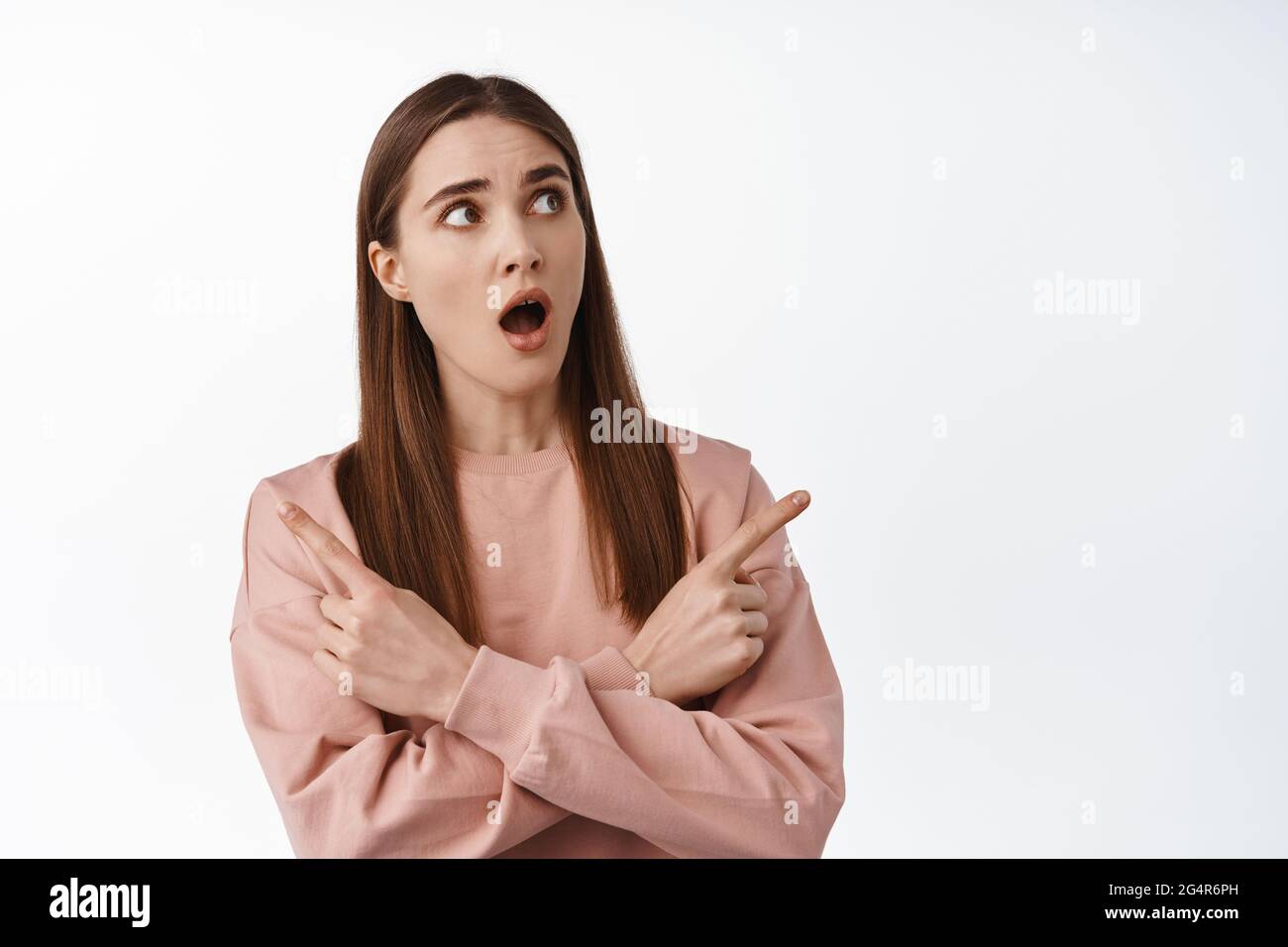 Image of young excited girl, gasping amazed, pointing sideways two ways ...