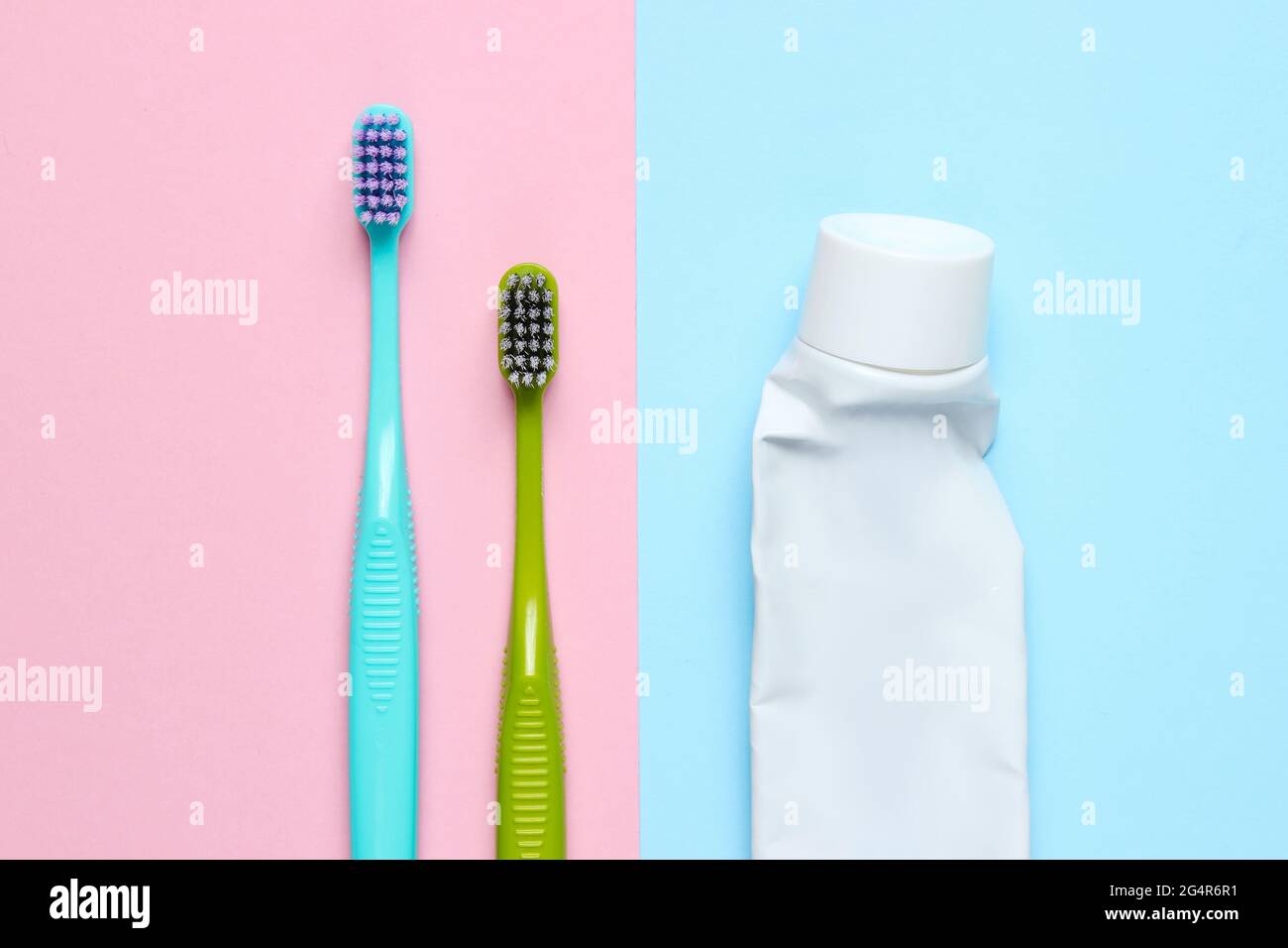 Two toothbrushes with a tube of used toothpaste on pastel background ...