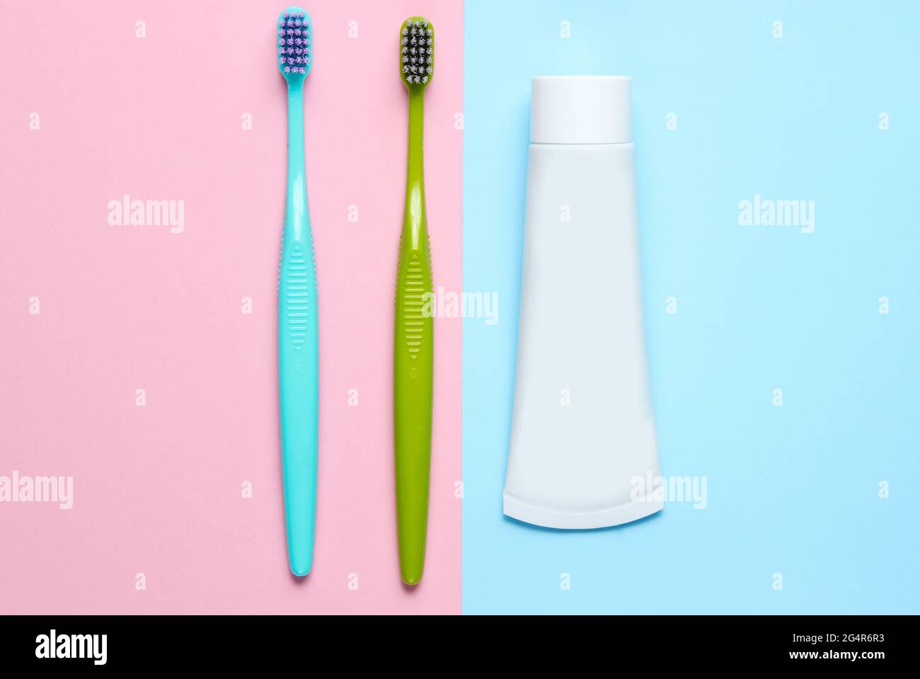 Two toothbrushes with a tube of toothpaste on pastel background. Top ...