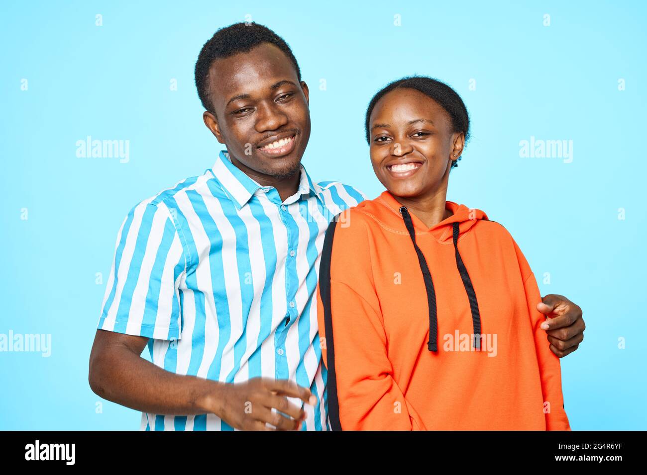 young african looking couple hugs blue background Stock Photo - Alamy