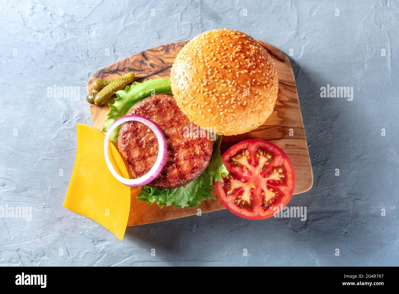 Burger ingredients, shot from above on a wooden board. Beef patty ...