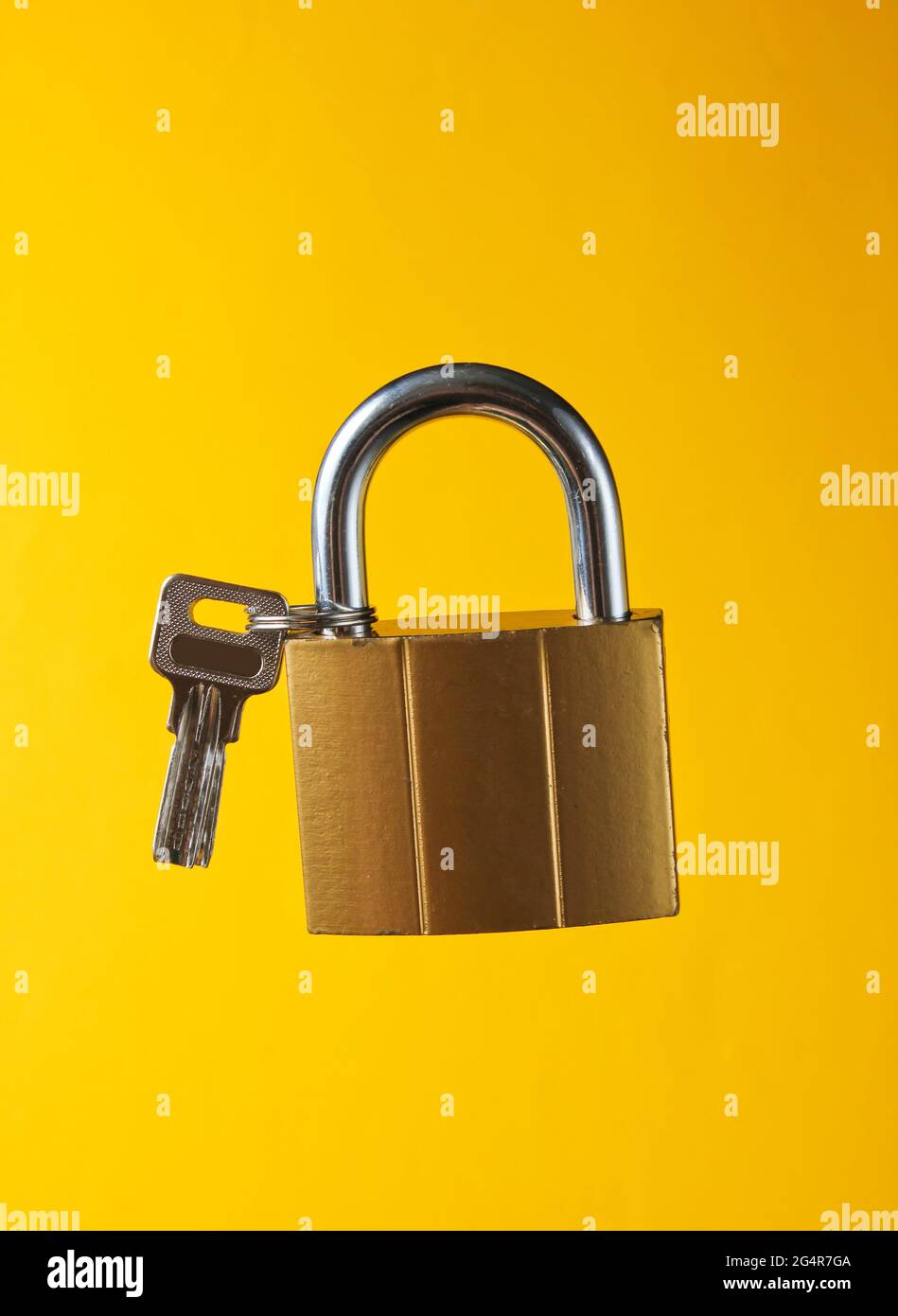 Metal lock with key on yellow background Stock Photo - Alamy