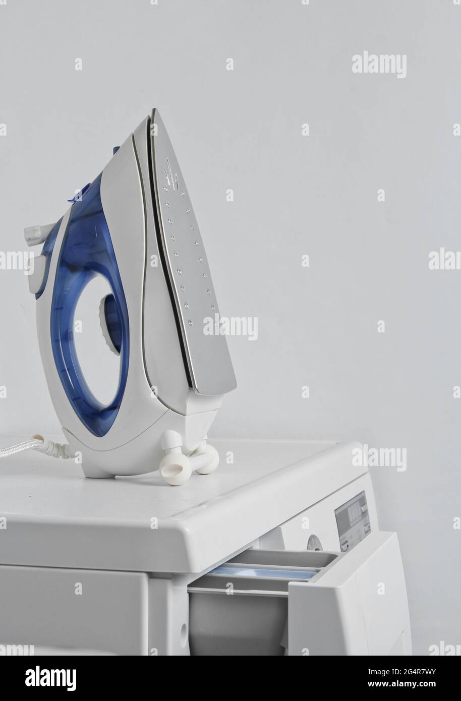Iron standing on washing machine close up on white background Stock ...