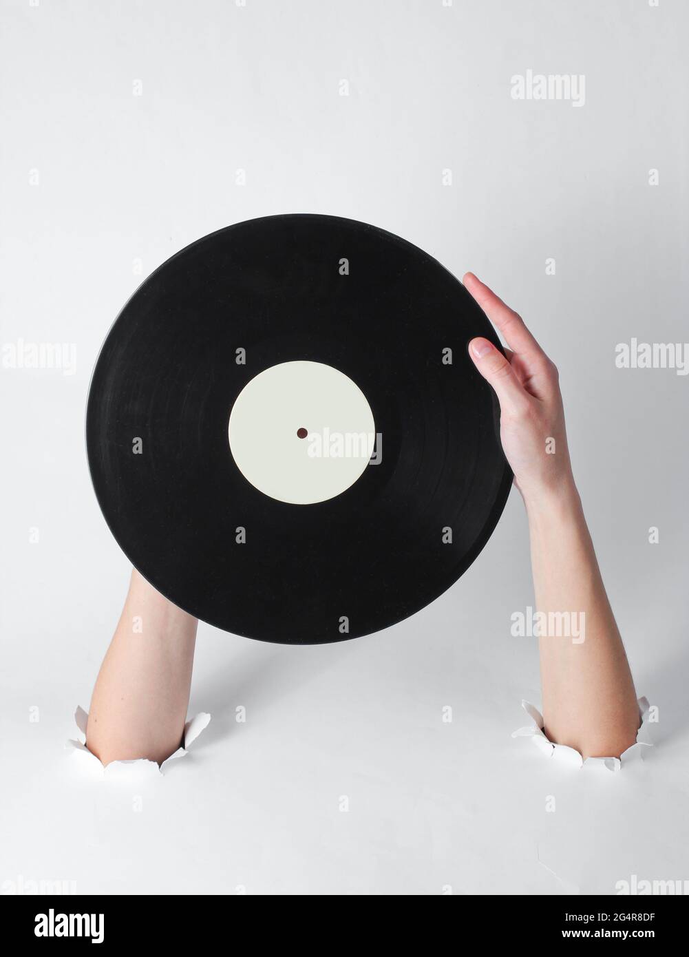 Female hands rotates a vinyl record through the torn holes of a white ...