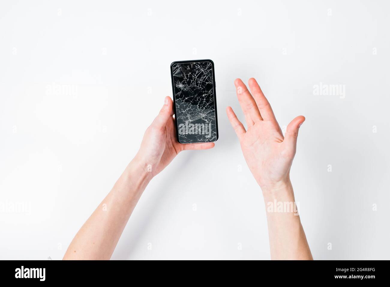 Female hands hold a smartphone with a broken screen through torn hole ...