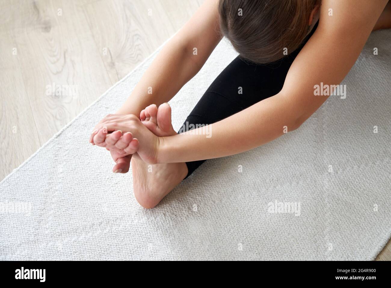 Top view of young woman practicing yoga, sitting in Seated forward bend ...