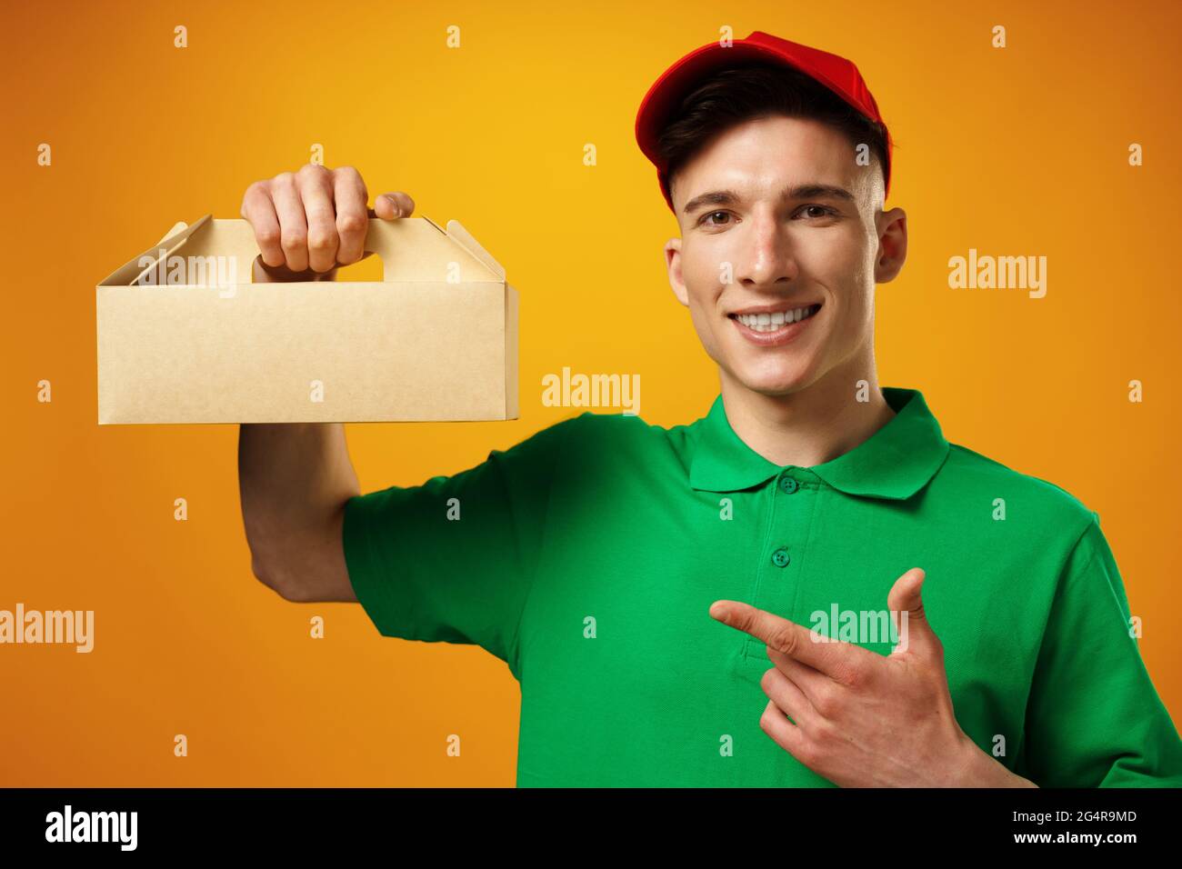 Delivery person holding parcel with food delivery against yellow ...
