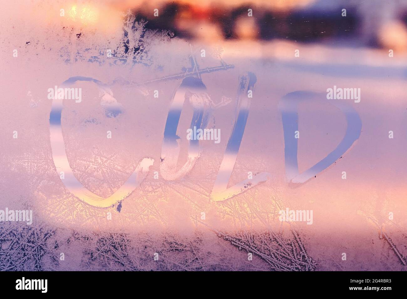 Word Cold on the frozen window glass. Hand written on the winter window ...