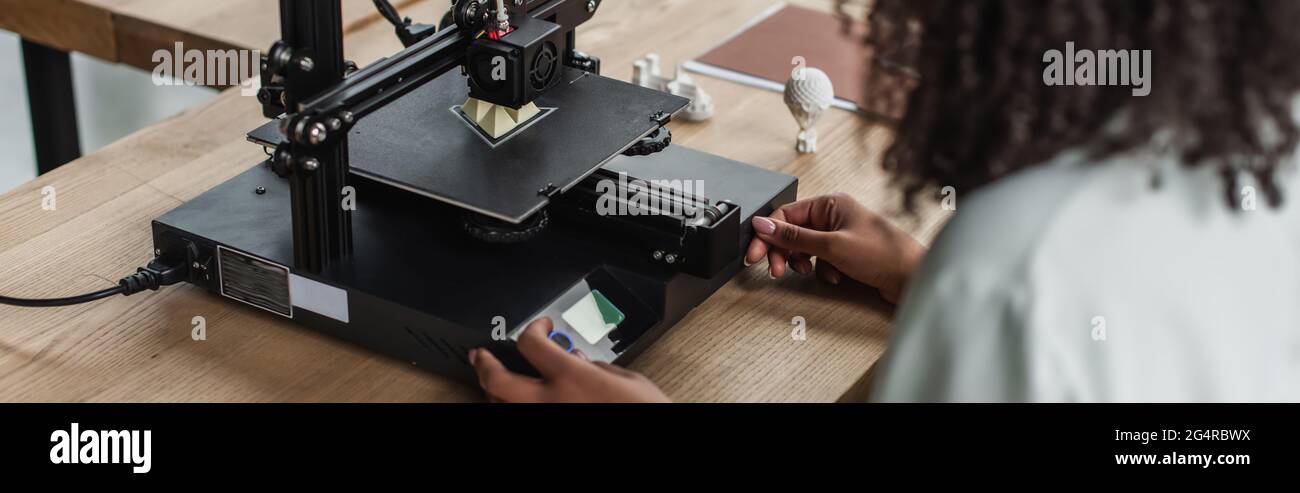 partial view of young designer working with 3D printer in modern office ...