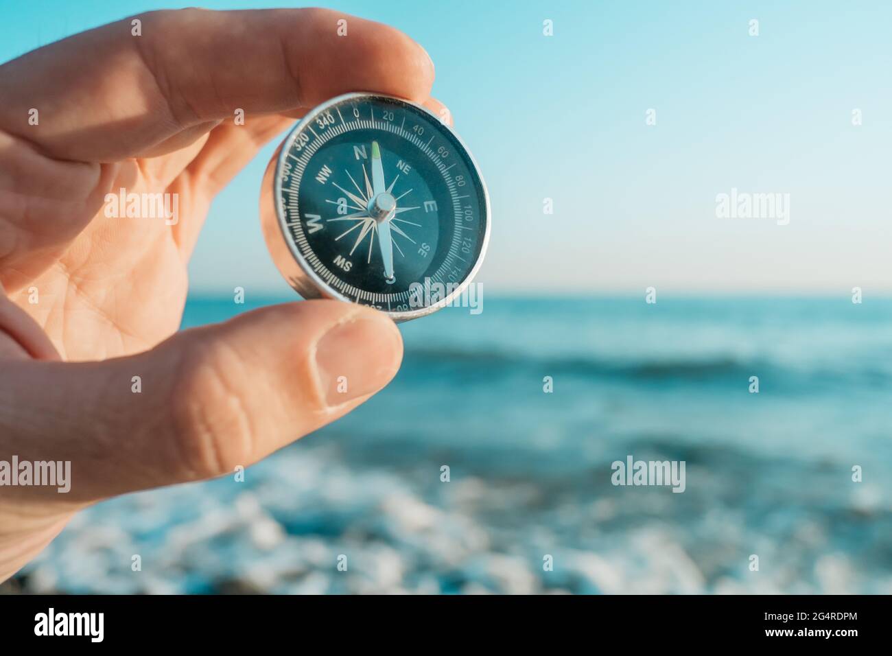 Man traveler holds a compass in his hand. In the background is a ...