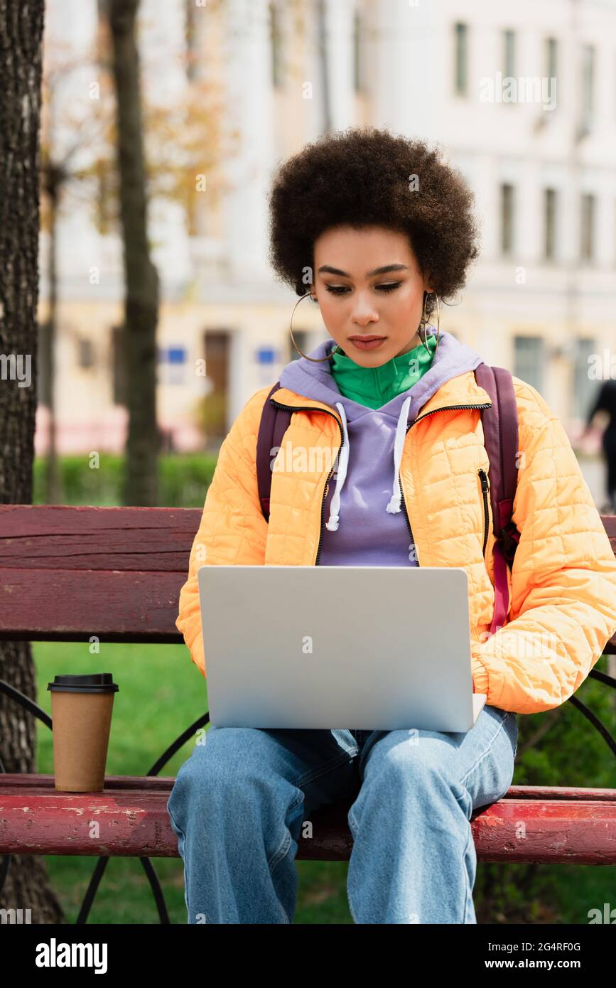 African american teleworker working on laptop near coffee to go on ...