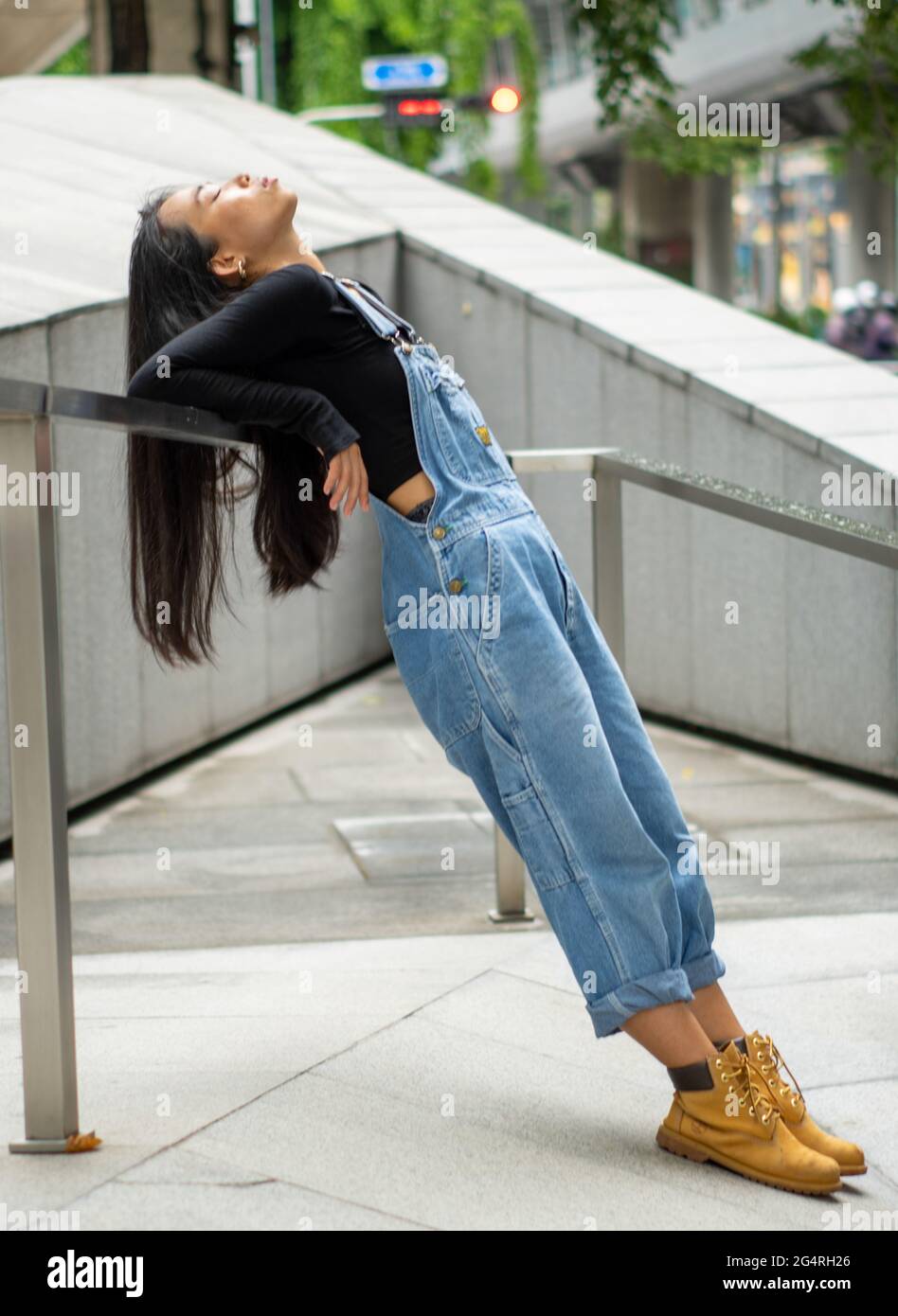 Asian girl in city leans on railings Stock Photo - Alamy