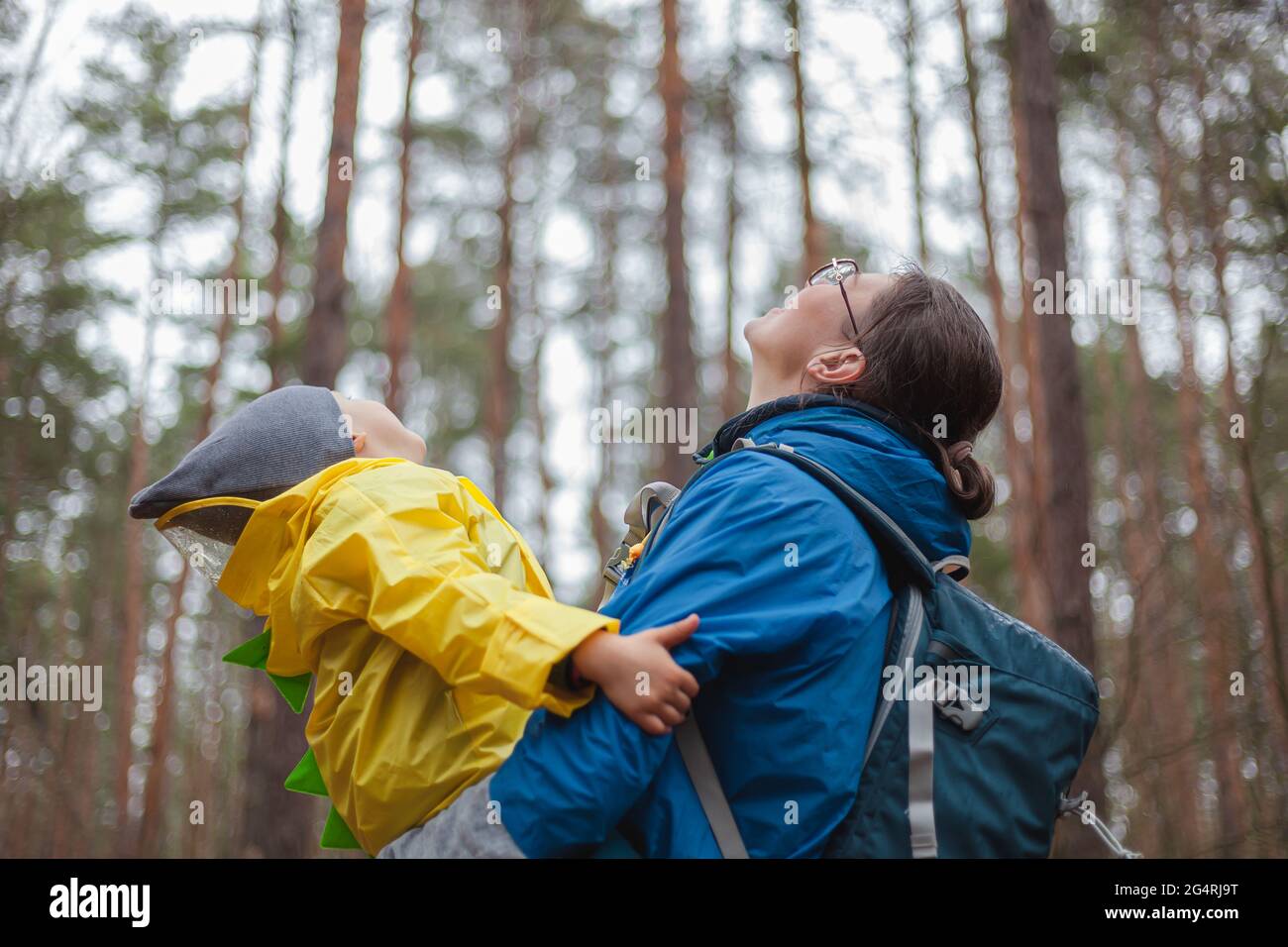 Happy family Mom and child walk in the forest after rain in raincoats ...