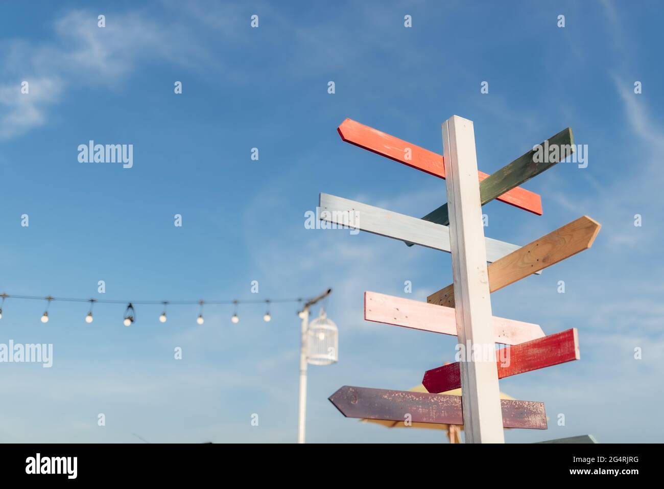 Guidepost with bright colored arrows in the sunlight with blue sky ...