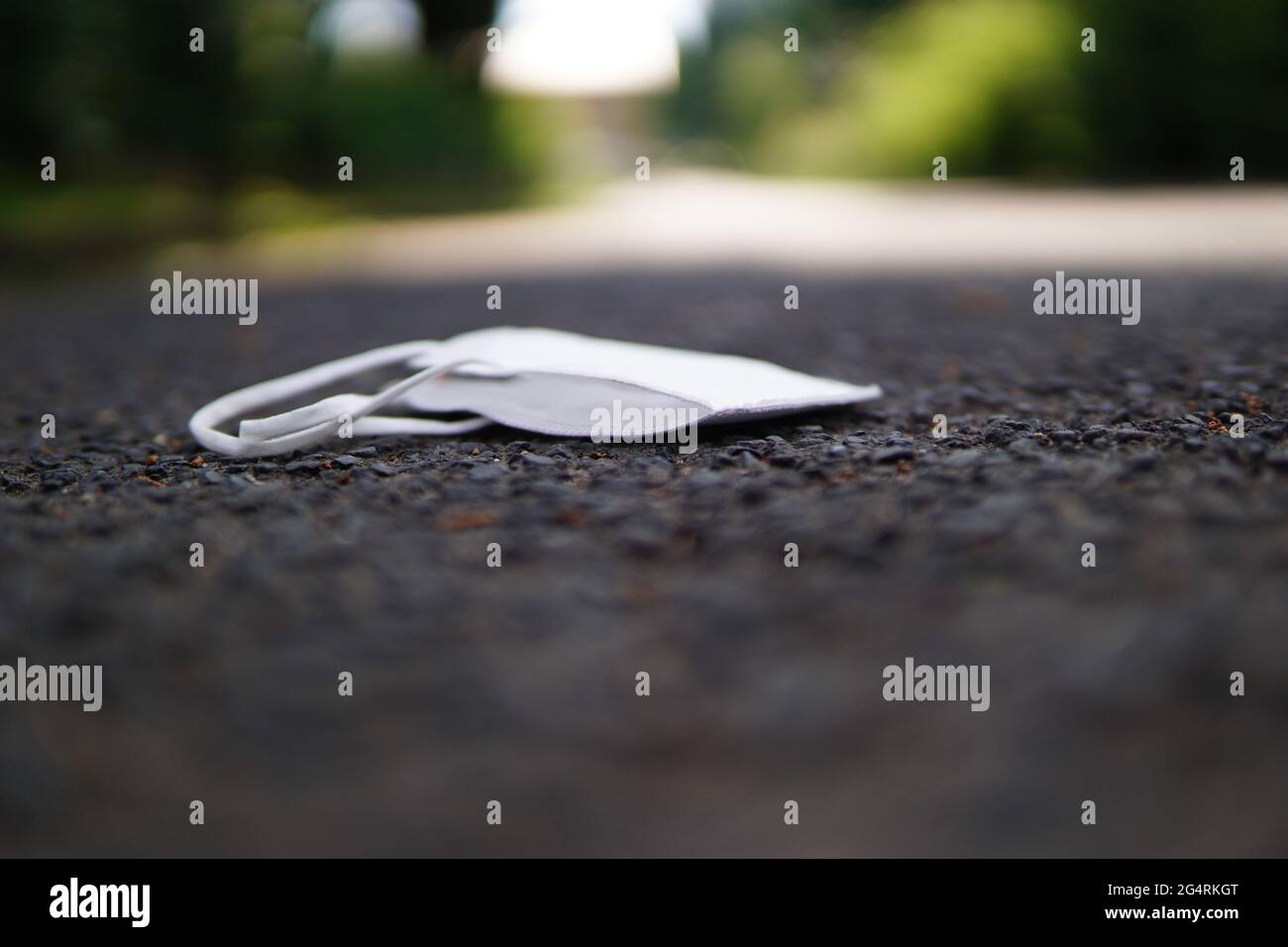 Selective focus of a face mask thrown on the asphalt Stock Photo - Alamy