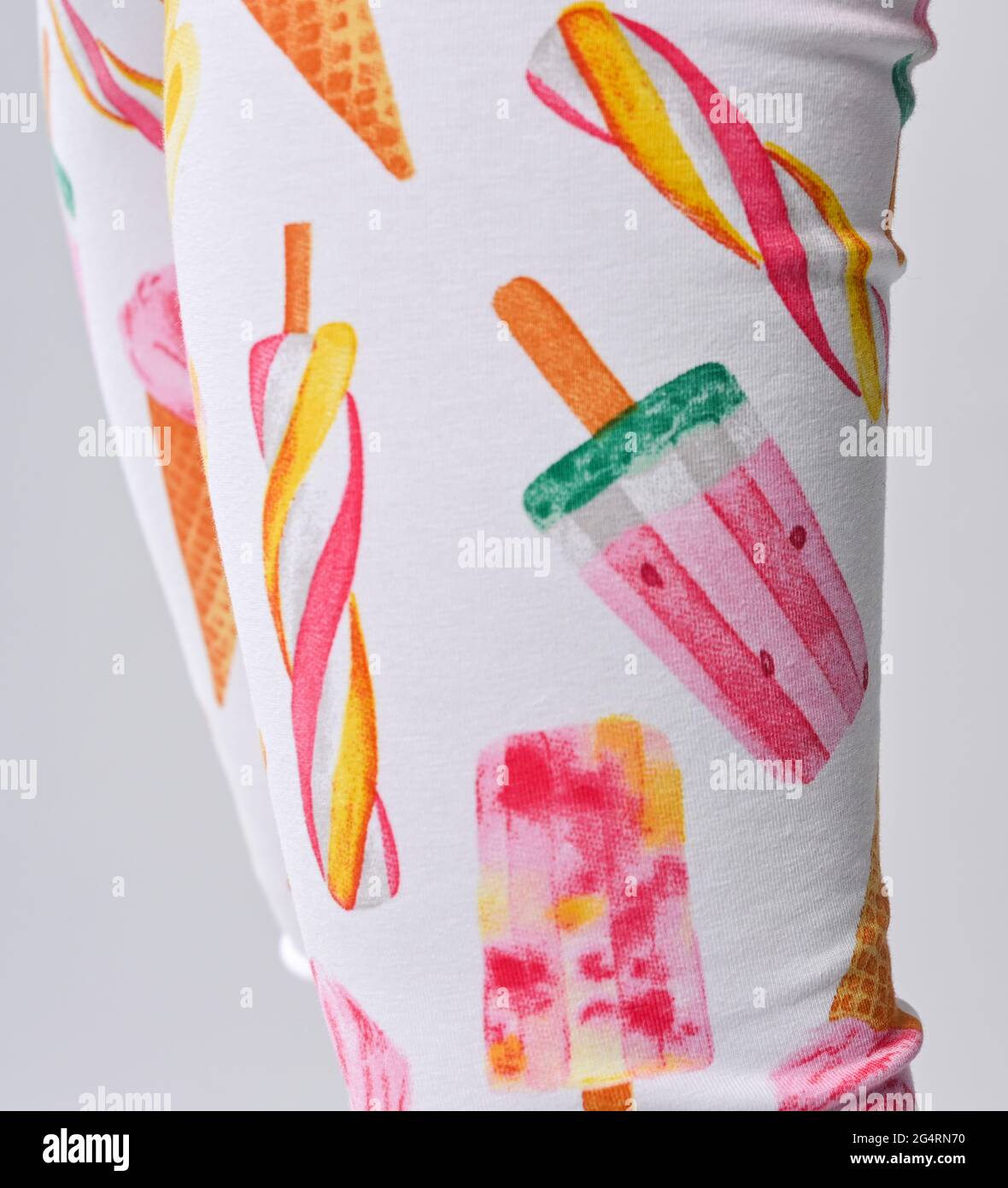 Close-up of kid girl legs in white pants with colorful ice-cream print ...