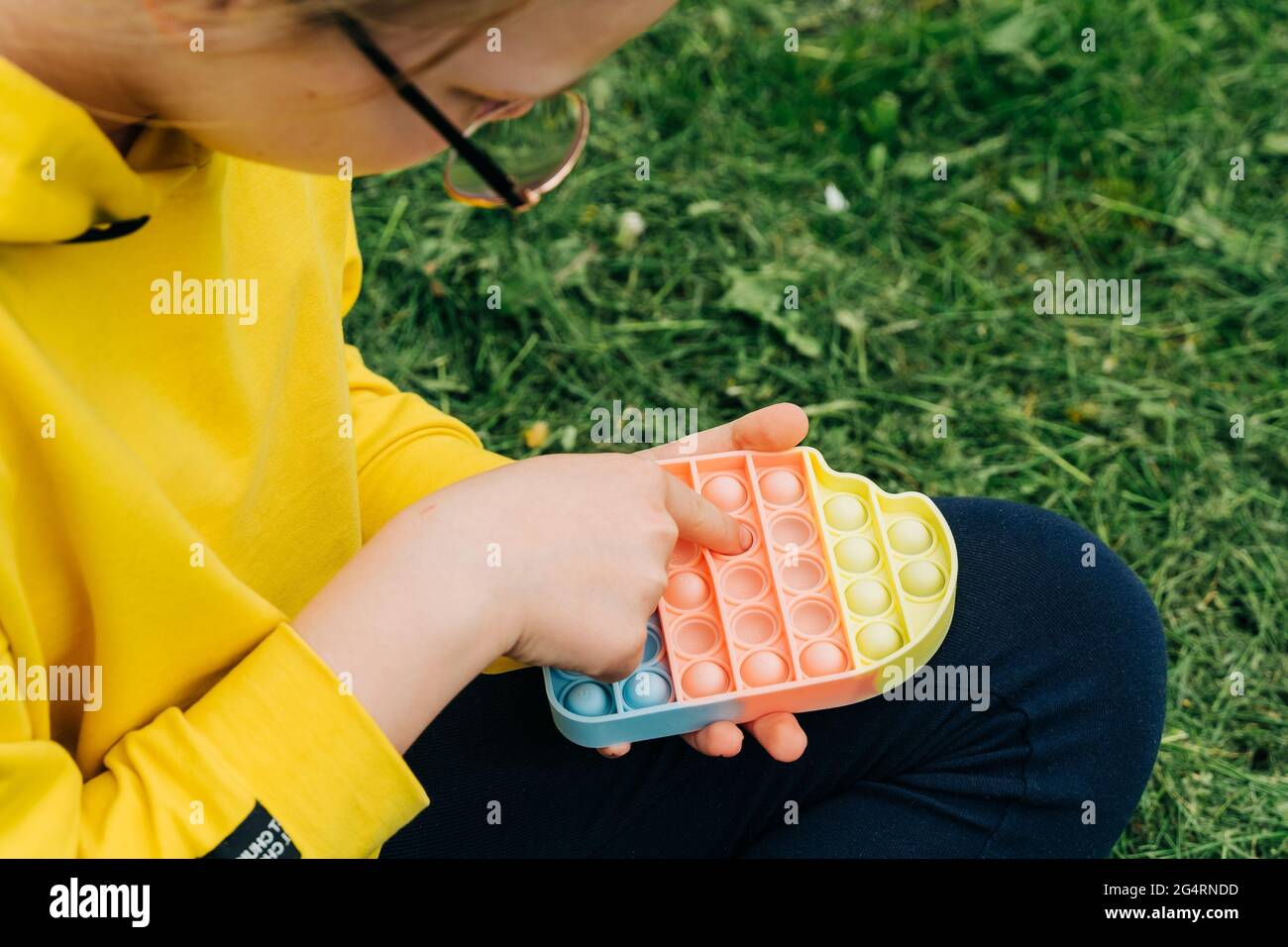 Anonymous child playing with colorful poppit sensory game. Close up of ...