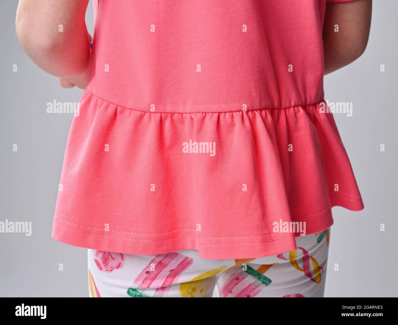 Close-up of kid girl pink t-shirt bottom and white pants with colorful ...