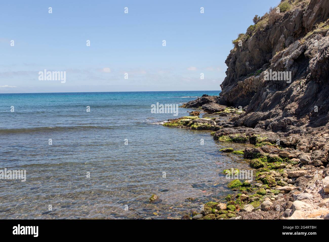 rocks and cliffs seen from below at the edge of a sea of transparent ...