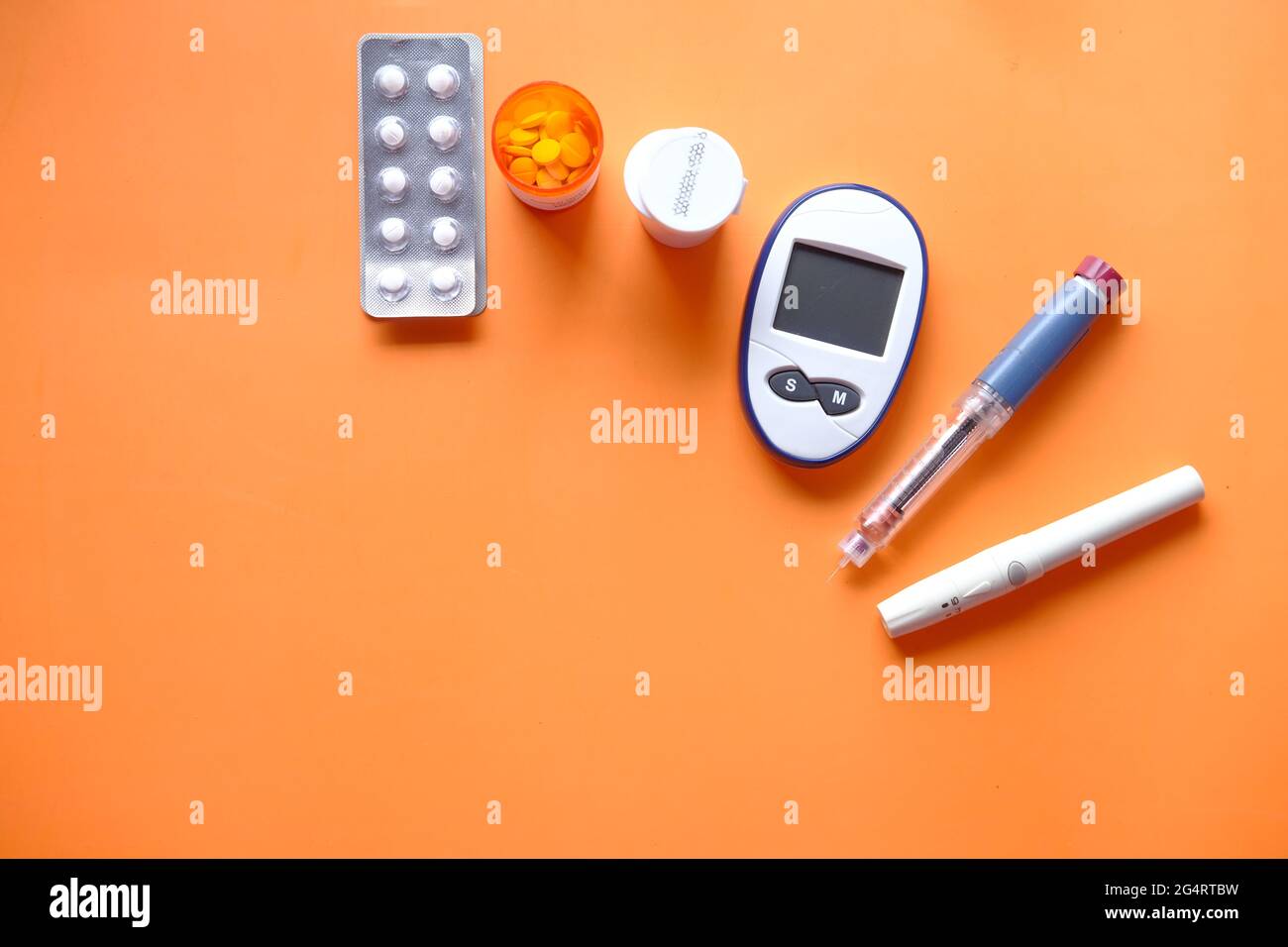 insulin pen, diabetic measurement tools and pills on orange background ...