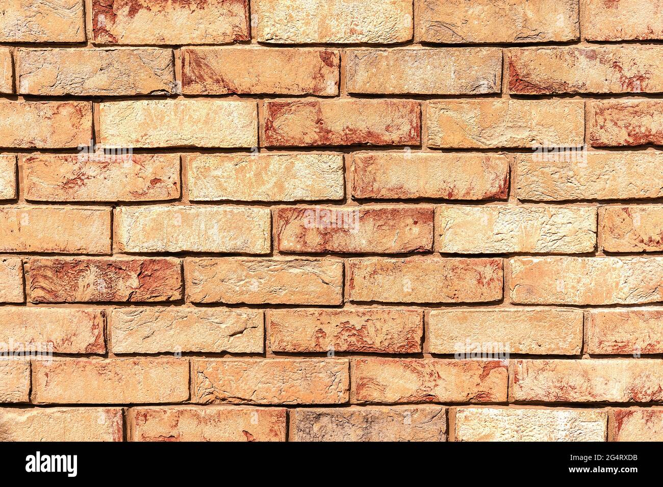 Sunlit weathered yellow and red brick wall. Brick texture for your ...