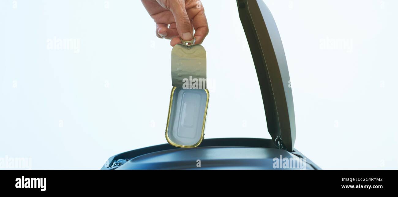 a young man throws an empty tin can in a home recycling bin, in a ...