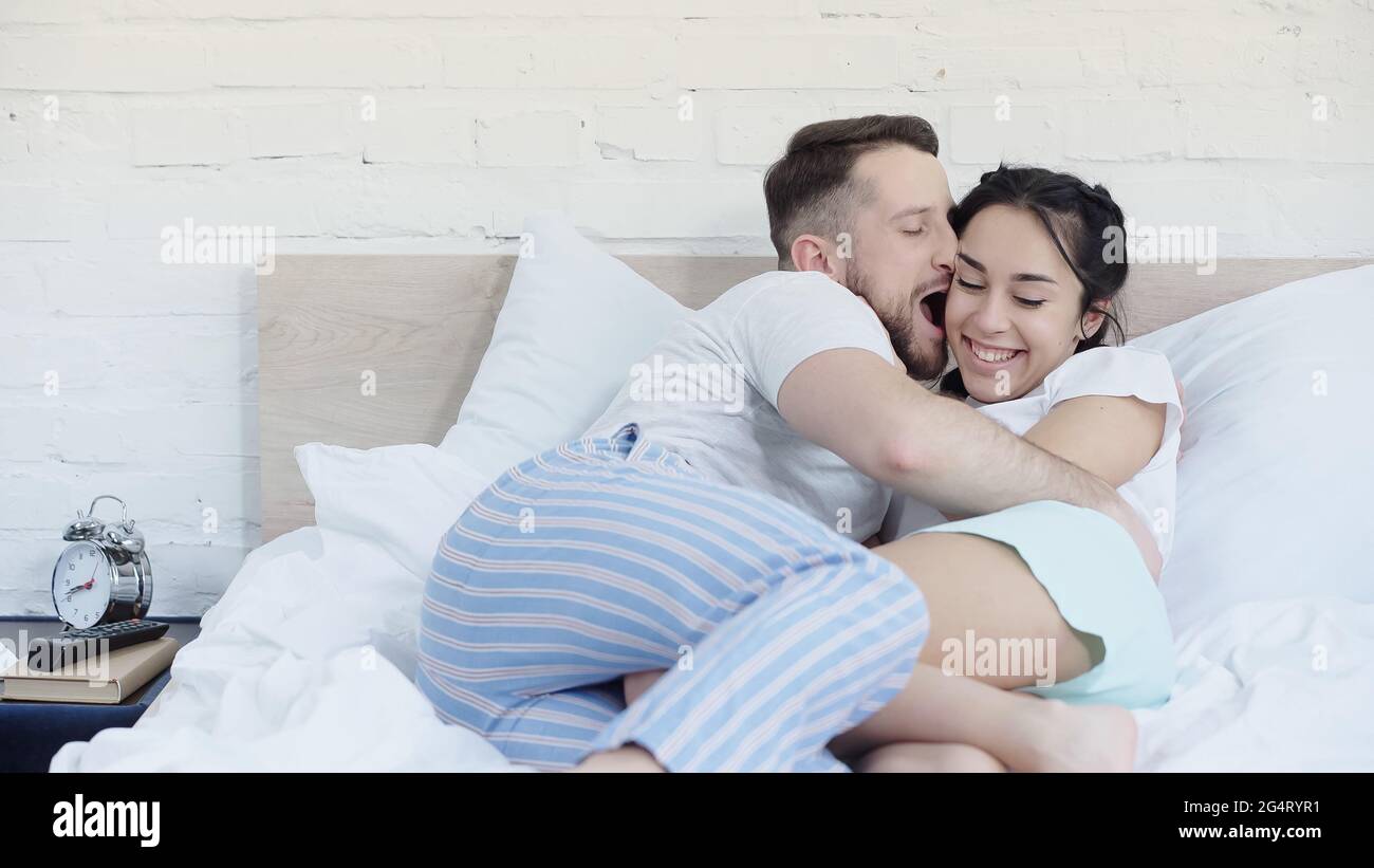 happy bearded man with open mouth hugging cheerful girlfriend with ...