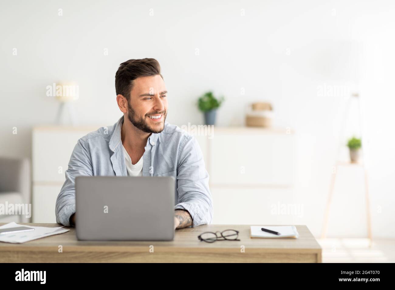 Happy freelance man working on laptop in home office, sitting on ...