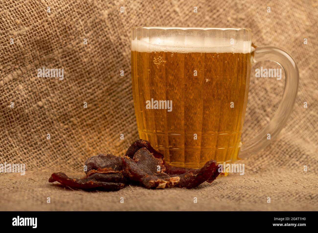 Pieces of dried caviar and a mug of beer on a table covered with a ...