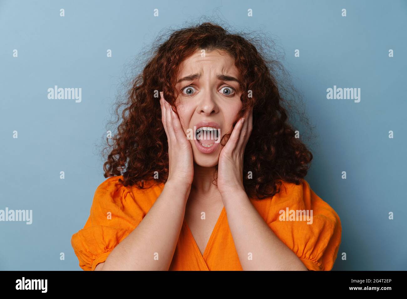 Shocked scared curly girl expressing surprise on camera isolated over ...