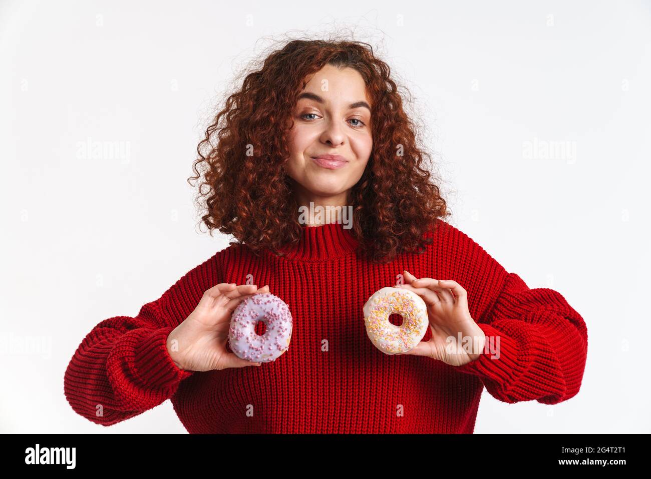 Joyful ginger curly girl making fun with doughnuts isolated over white ...