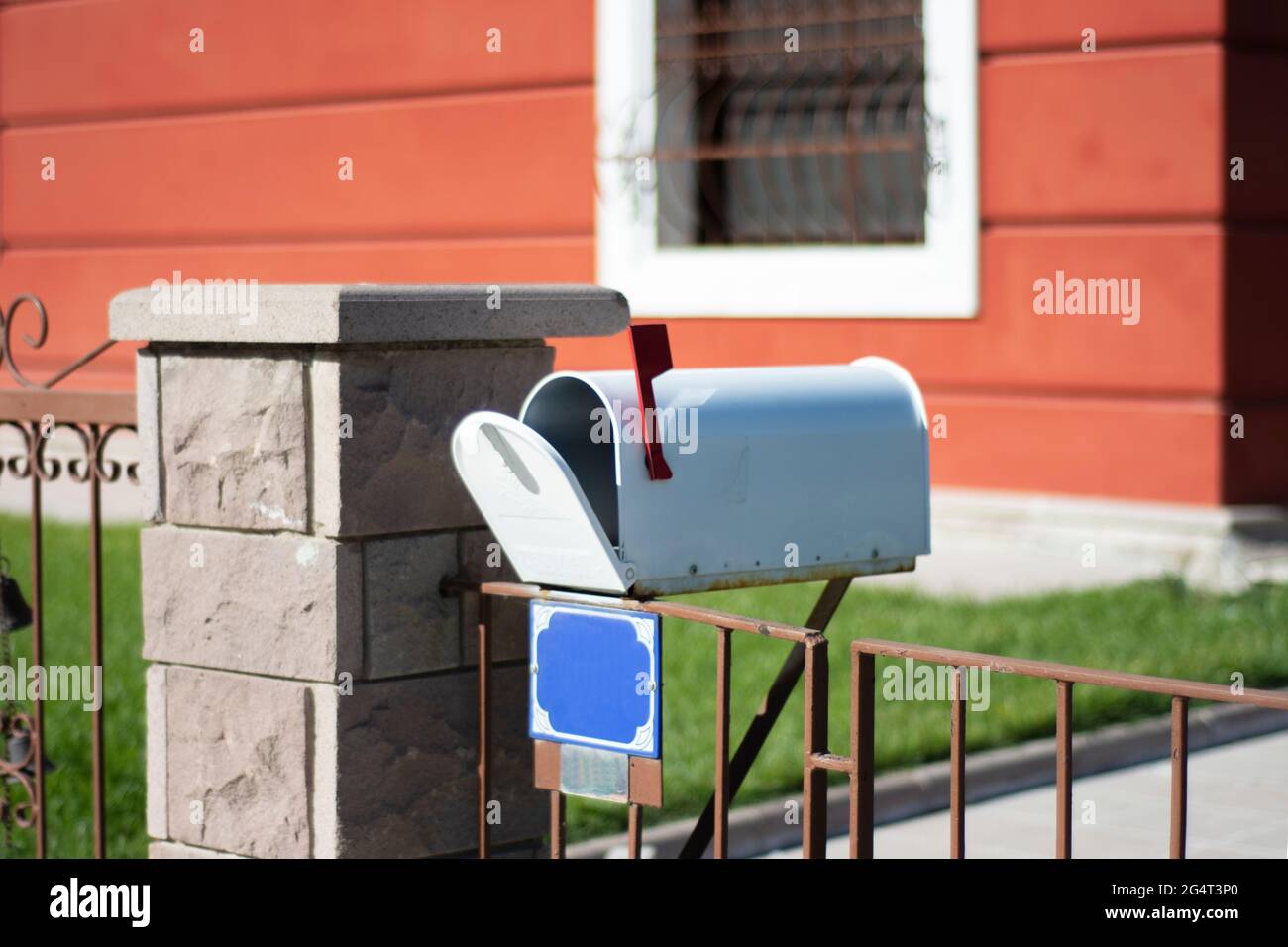 Just in front of the garden gate is an old-style mailbox with an open ...