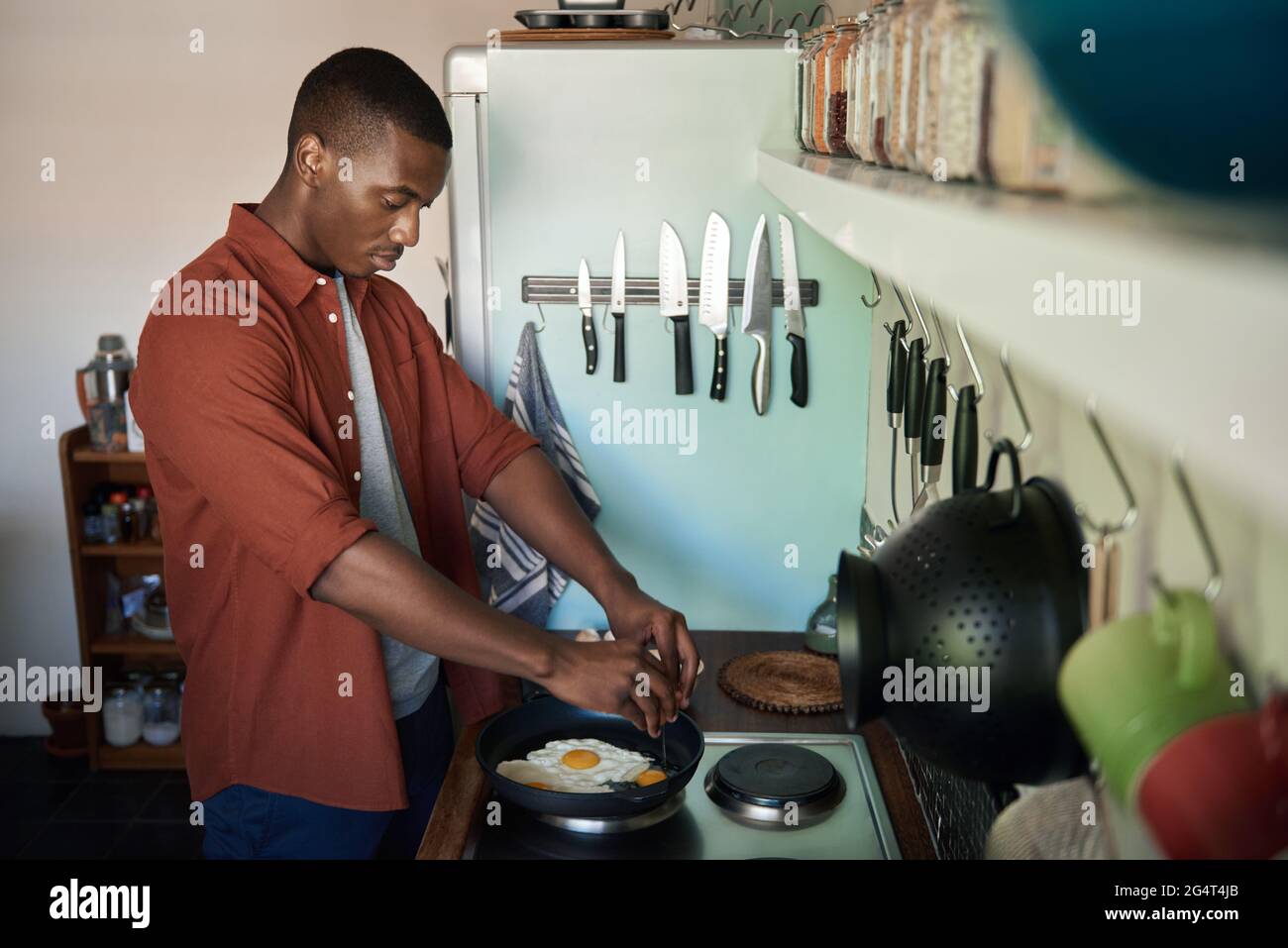 Young man cooking eggs hi-res stock photography and images - Alamy