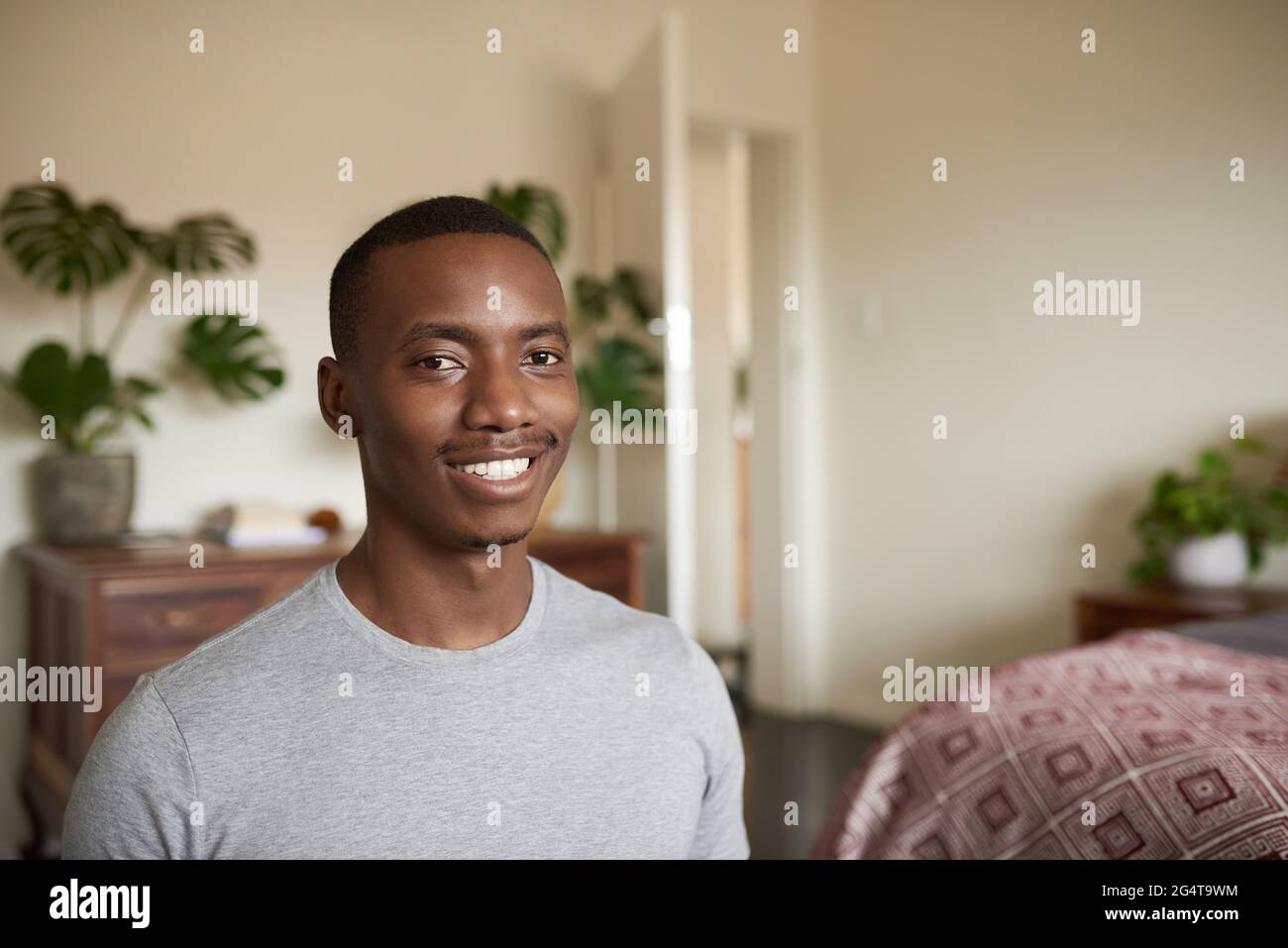 Young African man sitting in his bedroom and smiling Stock Photo - Alamy