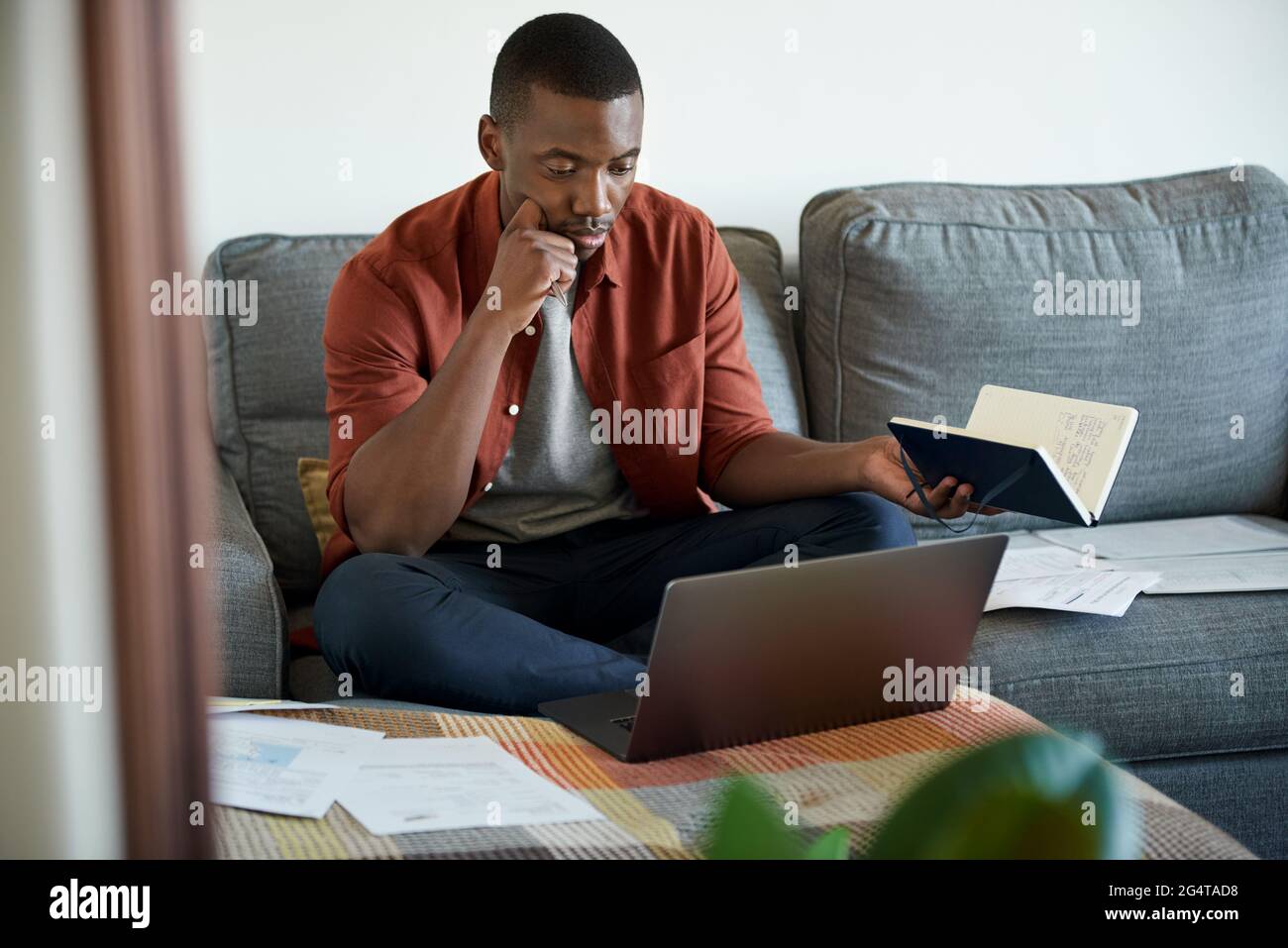Young African man working remotely from home on his sofa Stock Photo ...