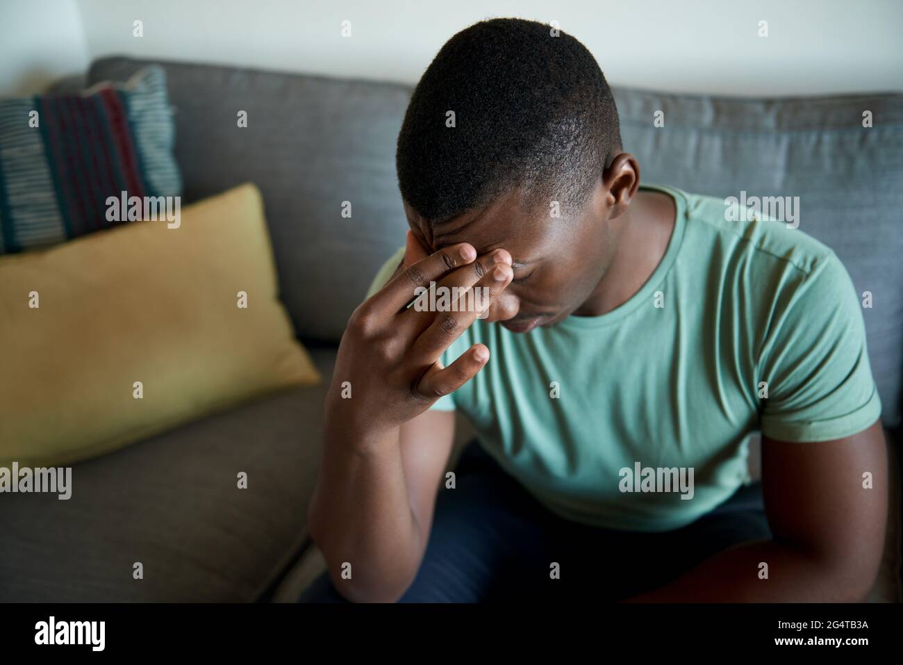 Young African man sitting on his sofa looking distraught Stock Photo ...