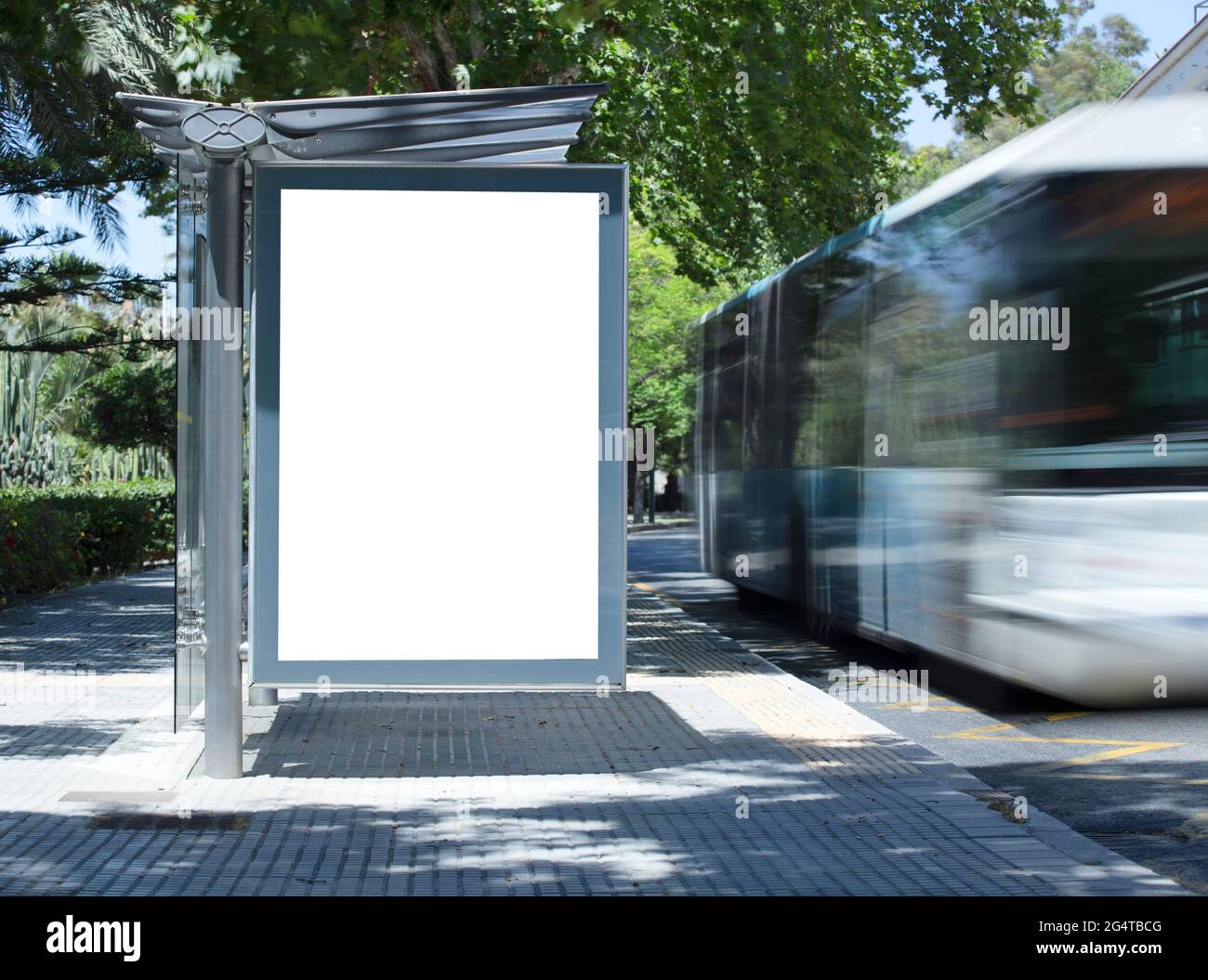 White blank vertical billboard at the bus stop on the city street. In ...