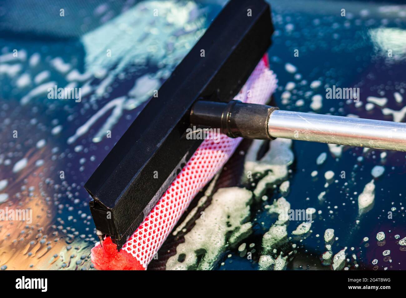 Closeup shot of washing the front window of a car with a mop in a self ...