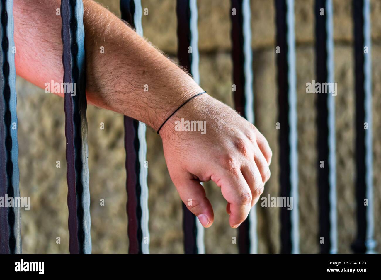 Close-up shot of a prisoner man holding hands on jail bars Stock Photo ...