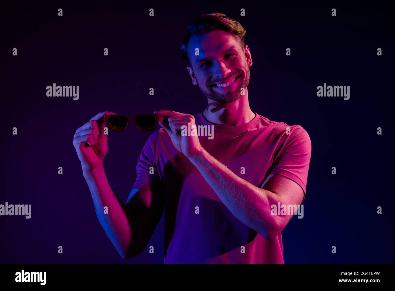 Portrait of attractive cheerful successful guy holding specs in hands ...