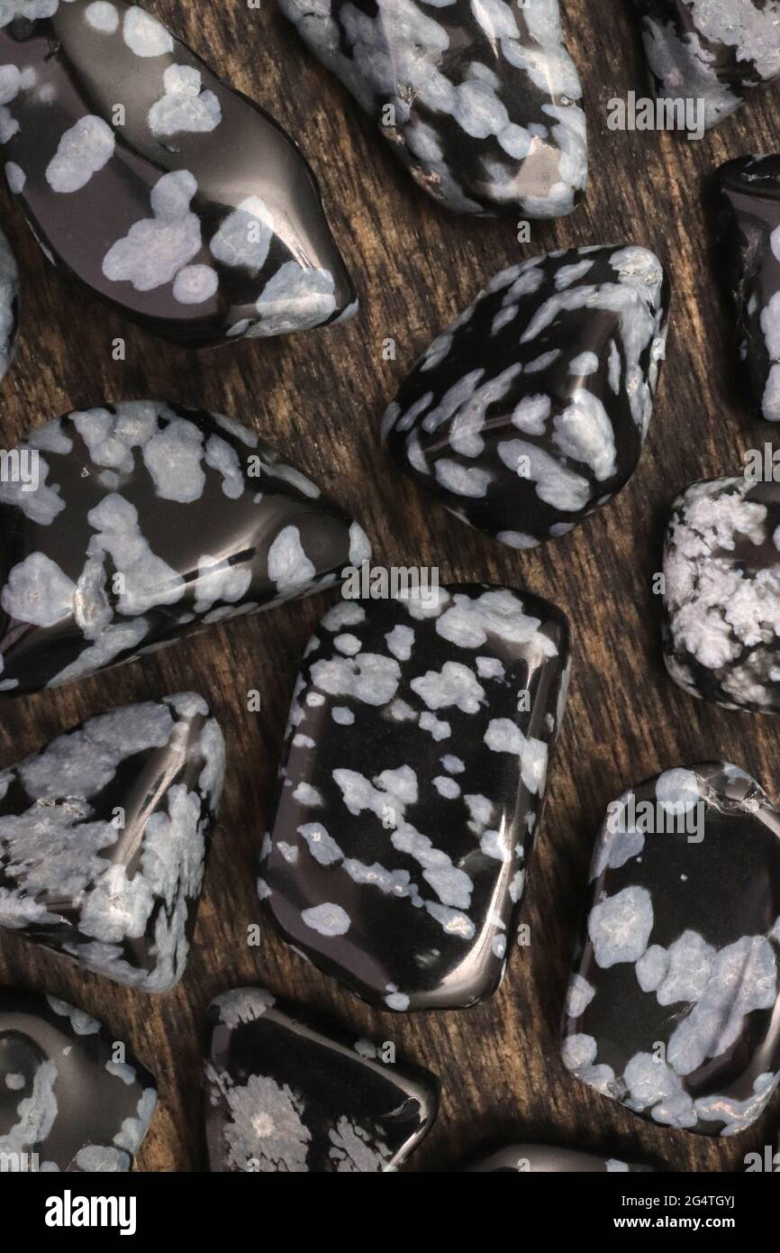 Snowflake rare jewel on black wood texture. Scarce mineral pebbles ...