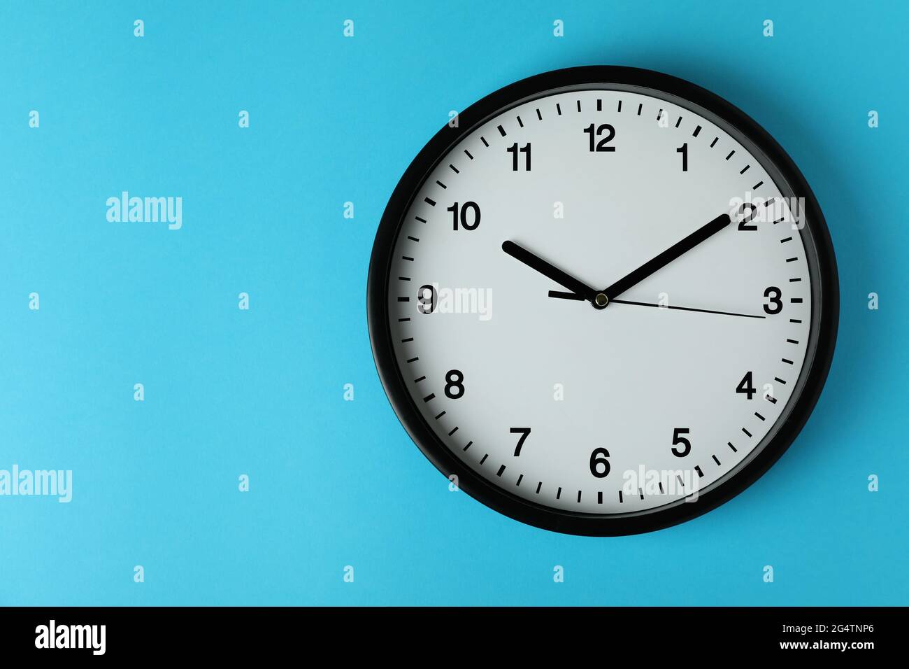 Standard black office clock on blue background Stock Photo - Alamy