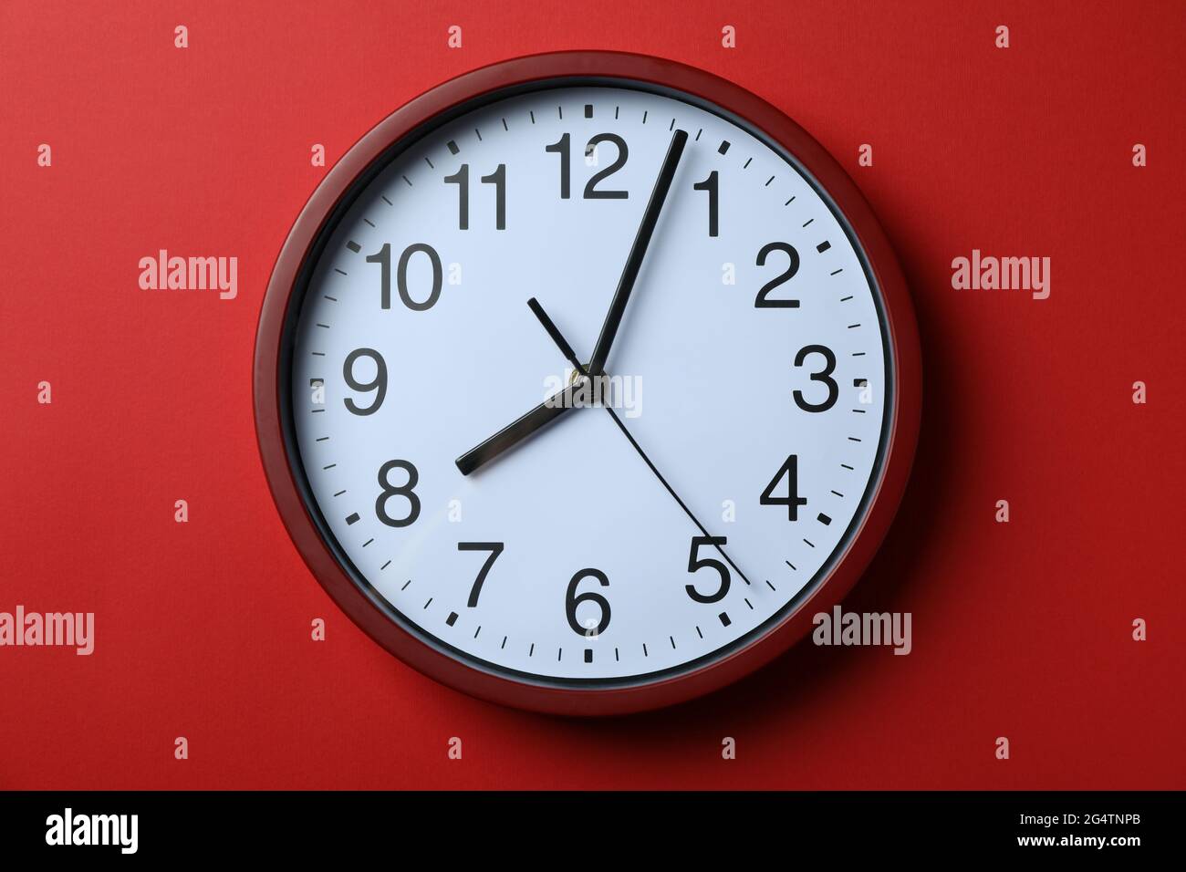 Standard red home clock on red background Stock Photo - Alamy