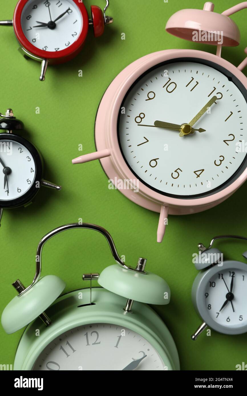 Different multicolor alarm clocks on green background Stock Photo - Alamy