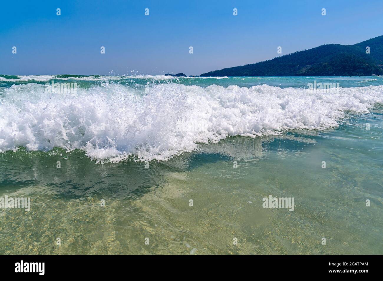 Waves in turquoise sea crashes over rocky shore at sunny day with clean ...
