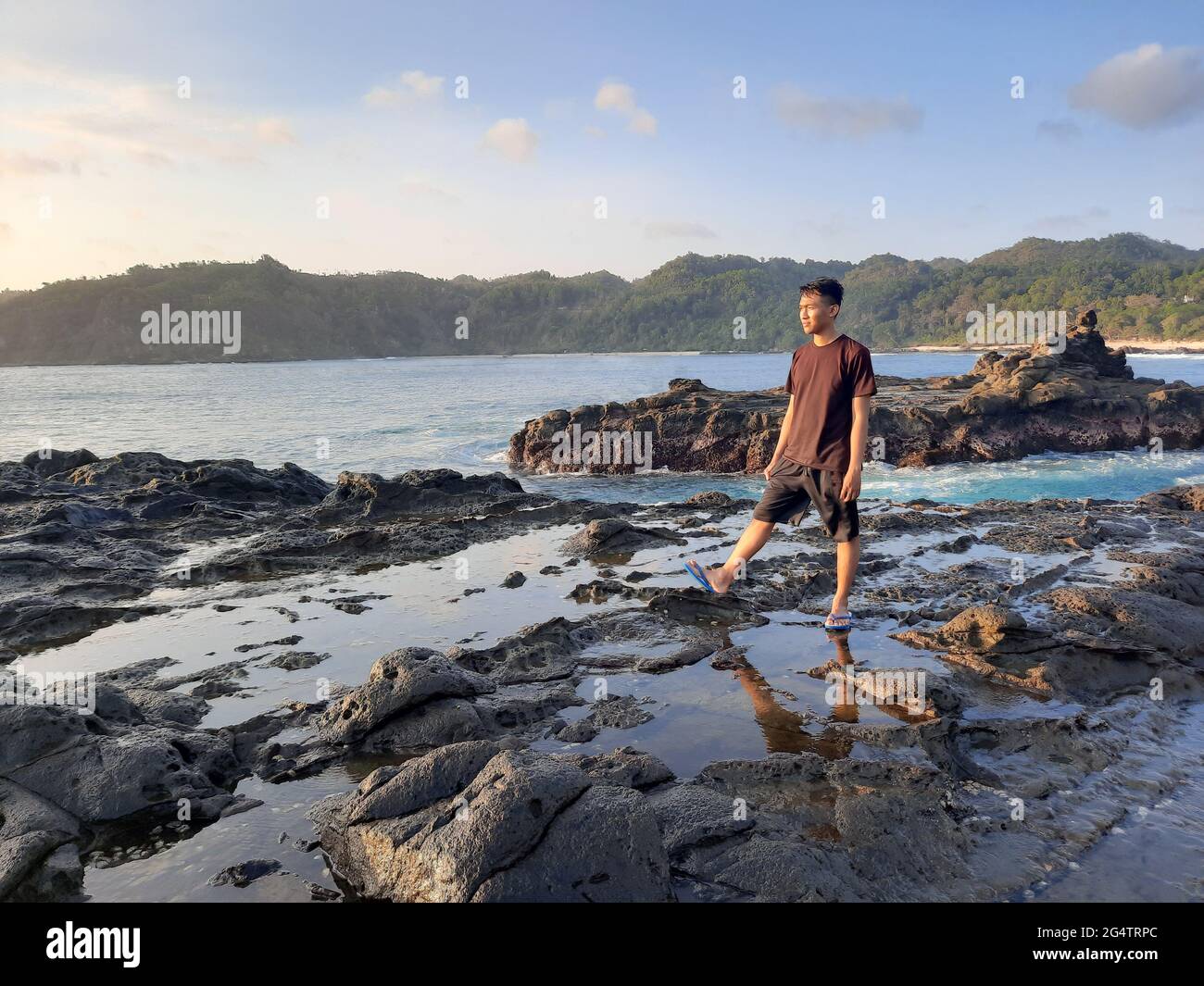 Young wet Asian man standing in water puddle on a rock plateau Stock ...
