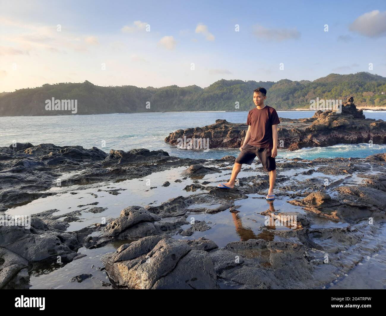 Young wet Asian man standing in water puddle on a rock plateau Stock ...