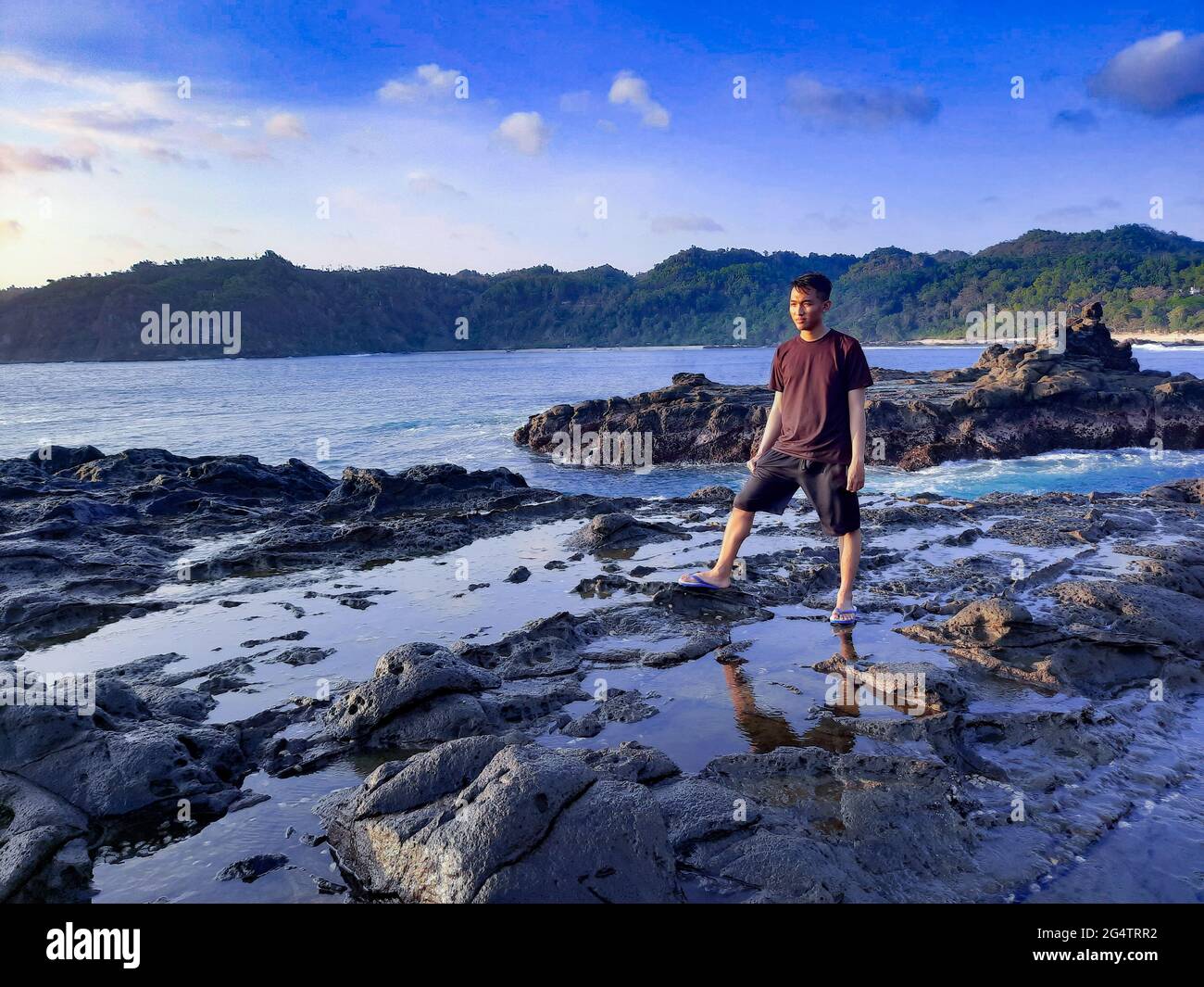 Young wet Asian man standing in water puddle on a rock plateau Stock ...