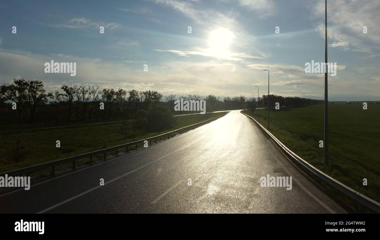 Drone rises above wet asphalt road for cars between sown fields Stock ...
