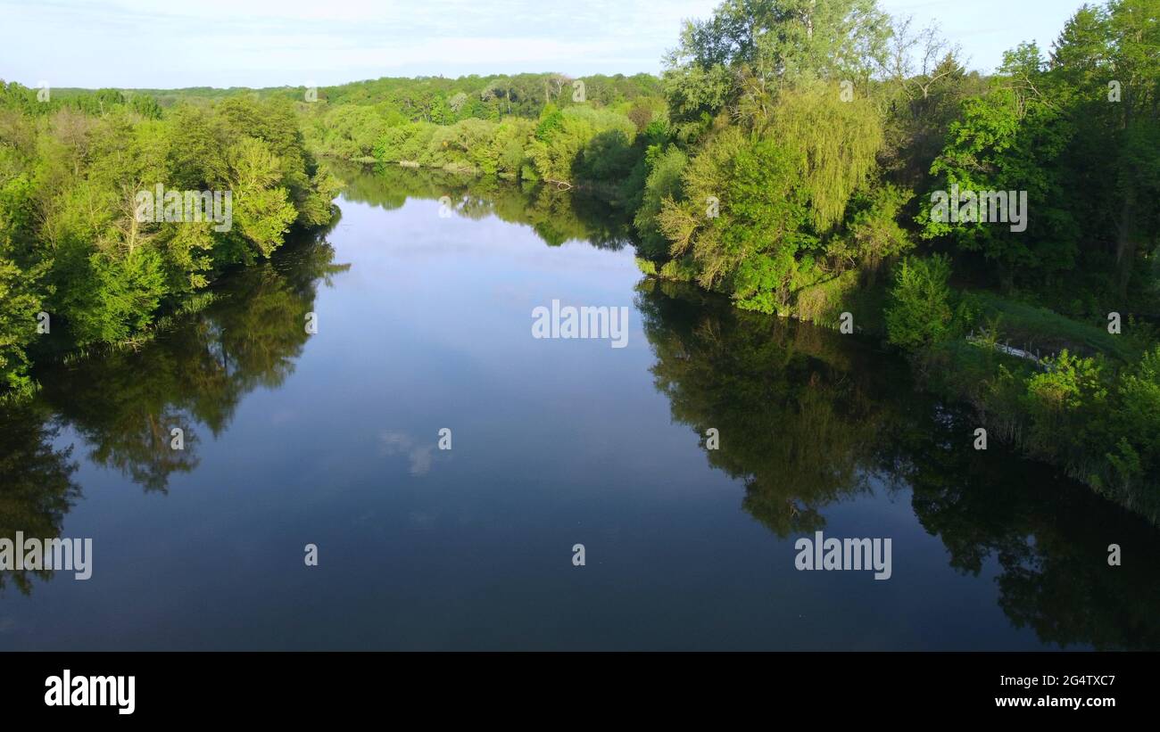 Aerial drone view flight over mirror smooth surface of river and trees ...
